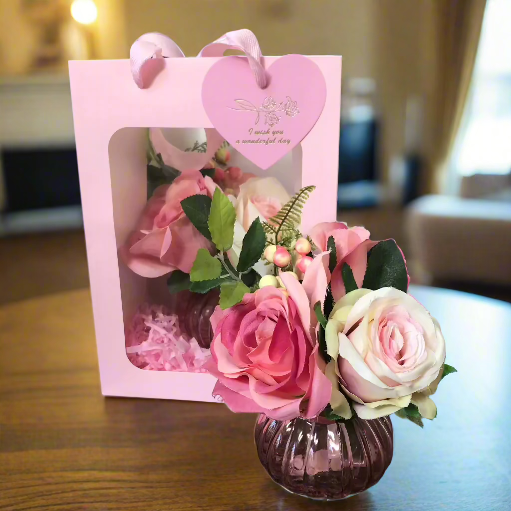 A small posy arrangement of pink silk roses in presention giftbag ...